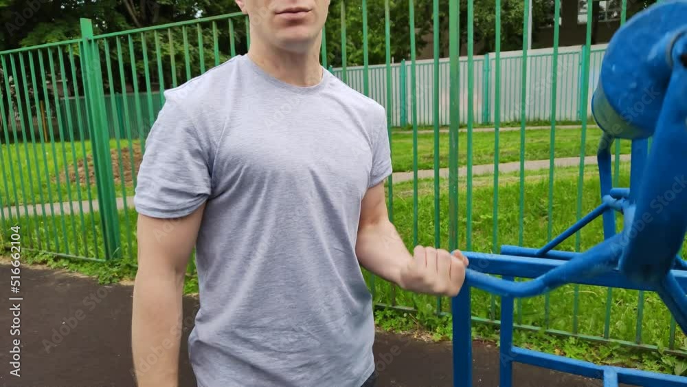 Young man trains biceps and triceps. Guy of athletic build does ...