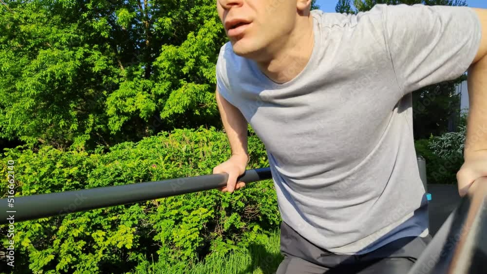 Young man trains on an outdoor sports field in city park. Guy does ...