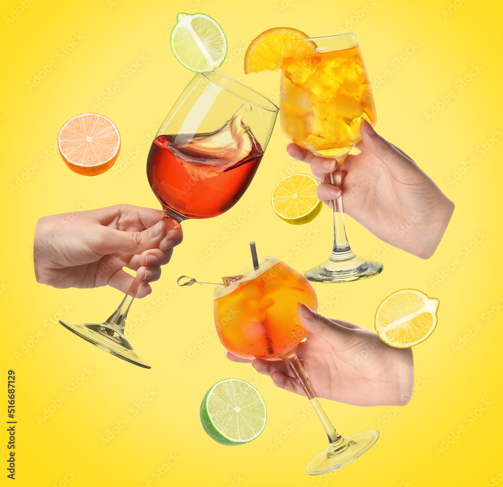 Hands with glasses of cold cocktails and citrus fruits on yellow ...