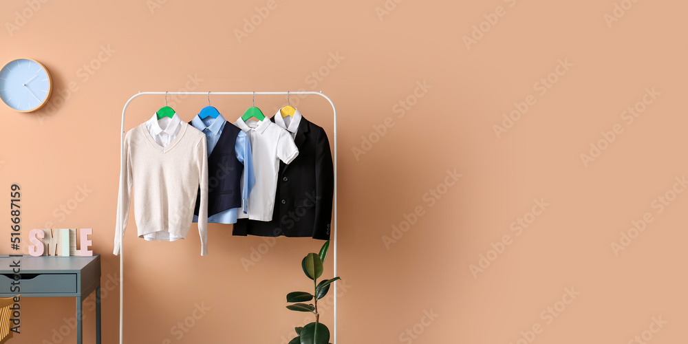 Rack with stylish school uniform near color wall. Banner for design ...