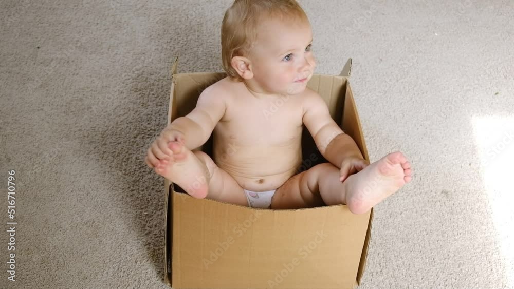 Baby in the Box. Pretty baby infant girl sitting inside a Cardboard box ...