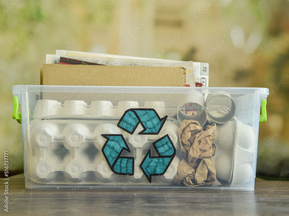 Transparent plastic container with recycle sign full of wastepaper on ...