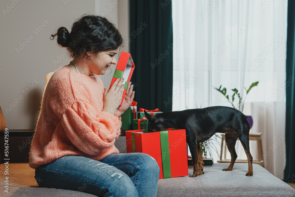 Happy young woman giving present for her dog from a gift box. Concept ...