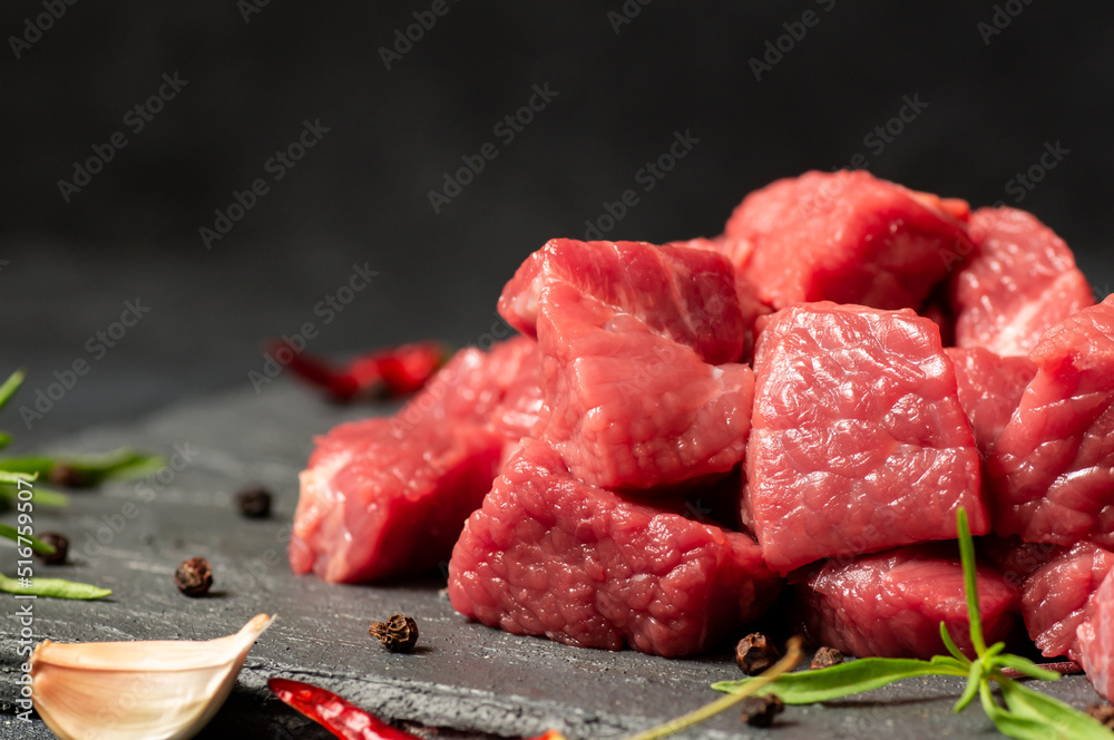 Diced cubed beef meat on stone board with thyme and peppers Stock Photo ...