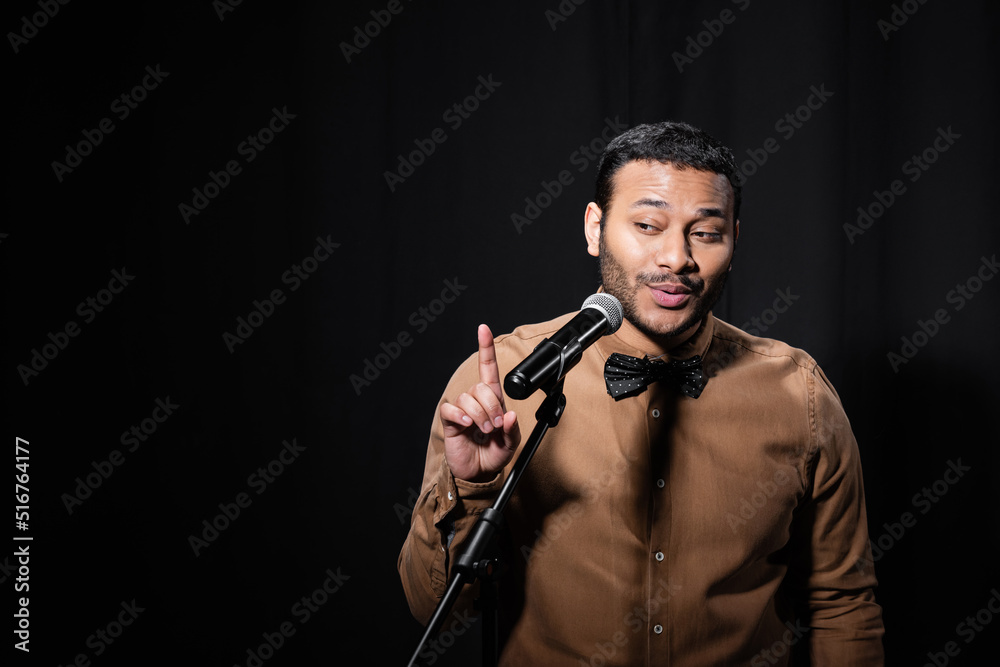 indian stand up comedian pointing with finger while telling jokes into ...
