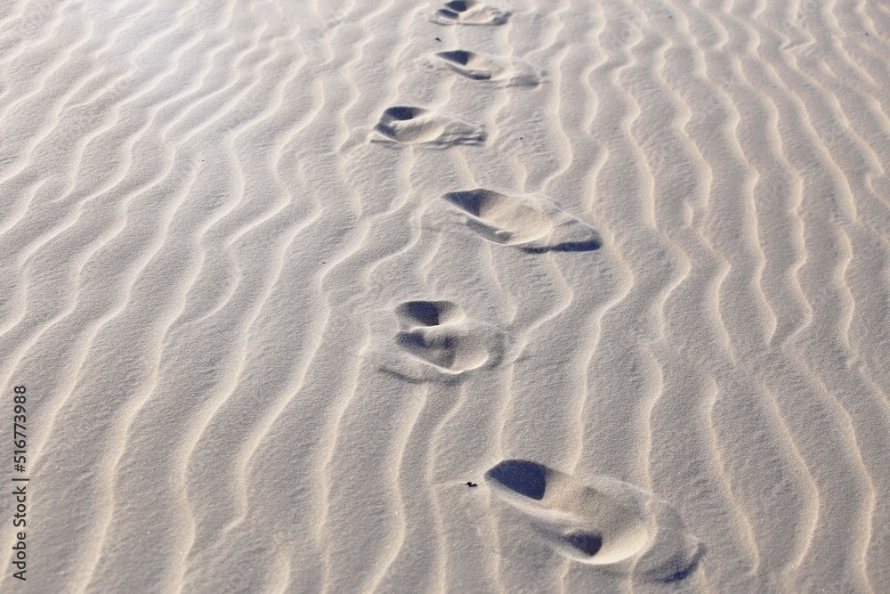 Adult person footprints in the desert dunes. Ripples in the sand made ...
