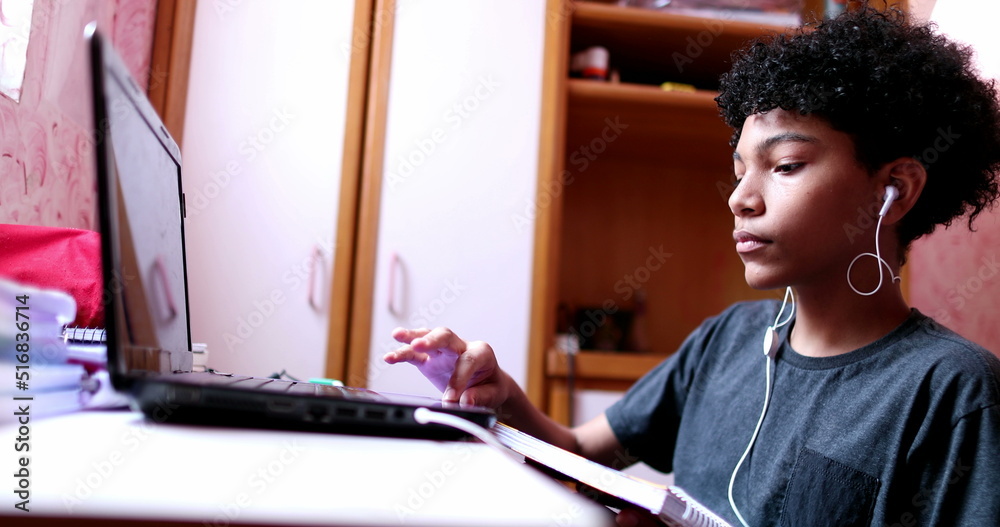 Child sitting down at desk opens laptop and turns computer on preparing ...
