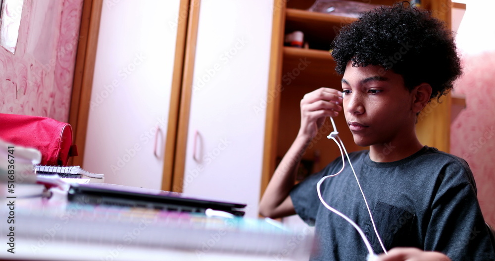 Child sitting down at desk opens laptop and turns computer on preparing ...