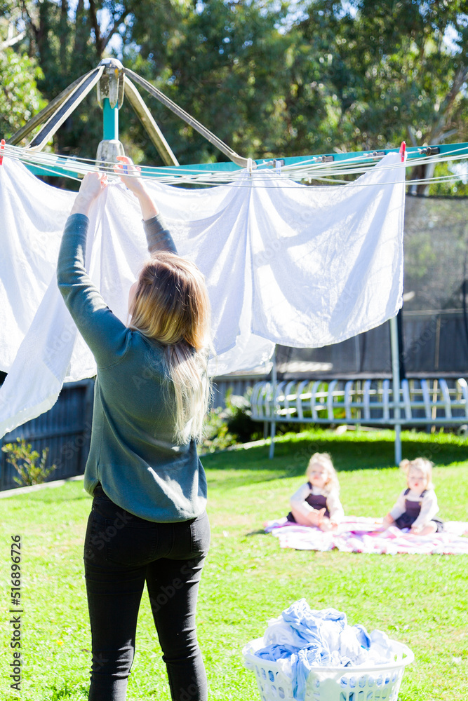 Stay at home mum hanging out washing in the backyard with kids picnic ...