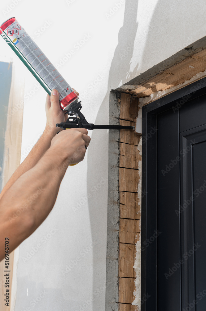 a man uses a spray gun with his hand and fills the gap with ...