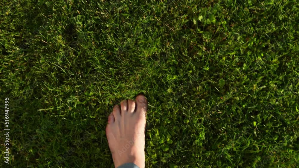 Barefoot caucasian man in jeans is walking on soft grass in garden ...