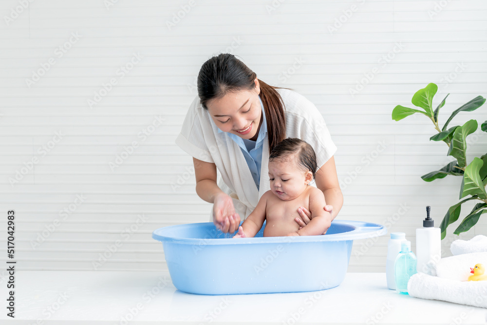 Asian mother Bathing her 7 month old daughter, which the baby smiling ...