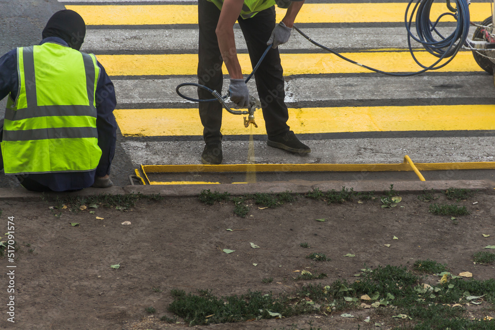 Workers are marking the pedestrian crossing with yellow paint ...