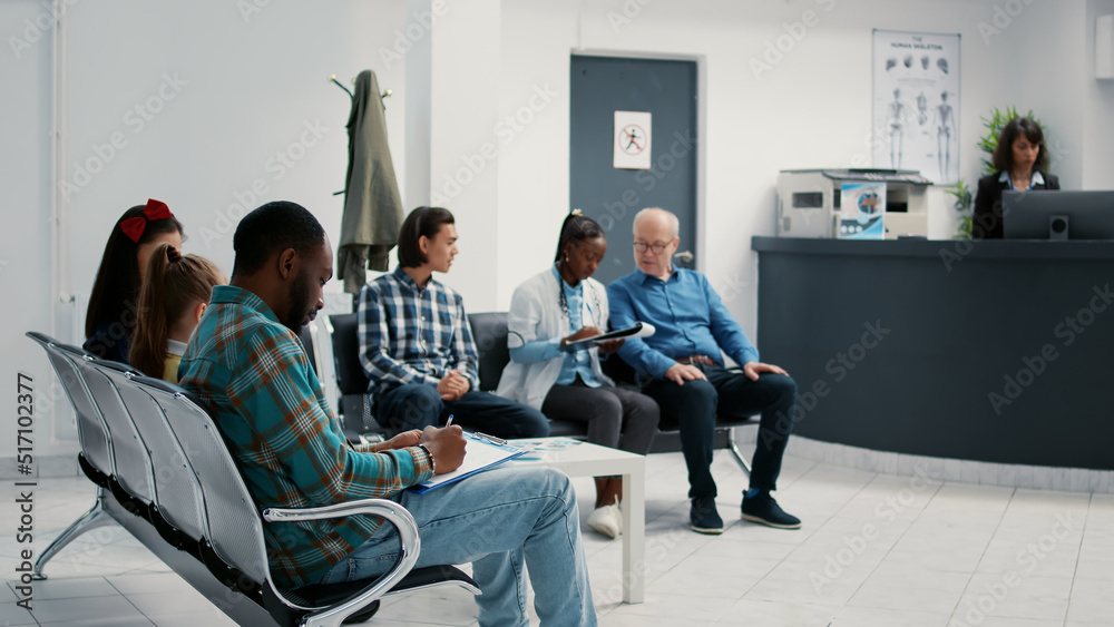 Diverse group of patients sitting in waiting room at hospital ...