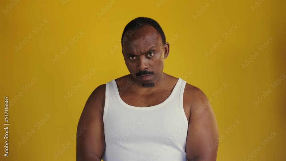 African Man Standing On A Yellow Background Man Plays With His Muscles On Camera Squeezes His