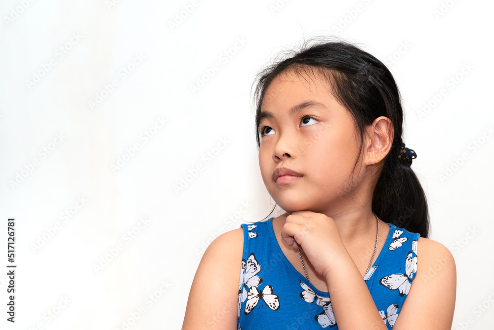 Portrait of cute Asian child girl is thinking, looking at the right side and slightly up, one ...