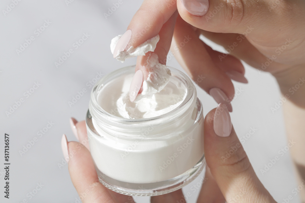 Close up of woman's hand is taking cream from a jar with her finger ...