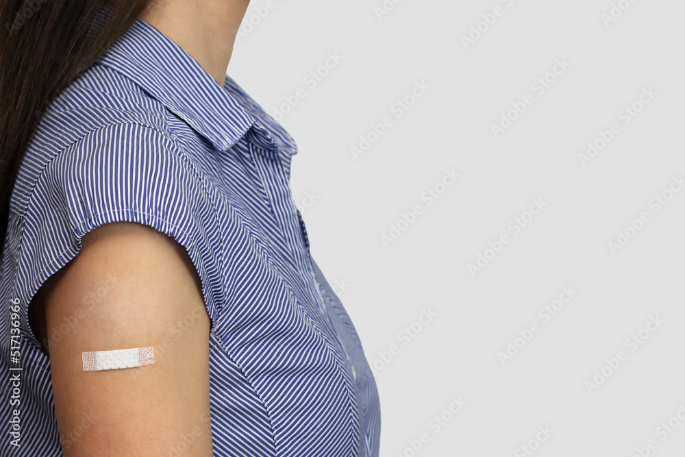 One medical patch on the arm of a young woman. Symbol of vaccination ...