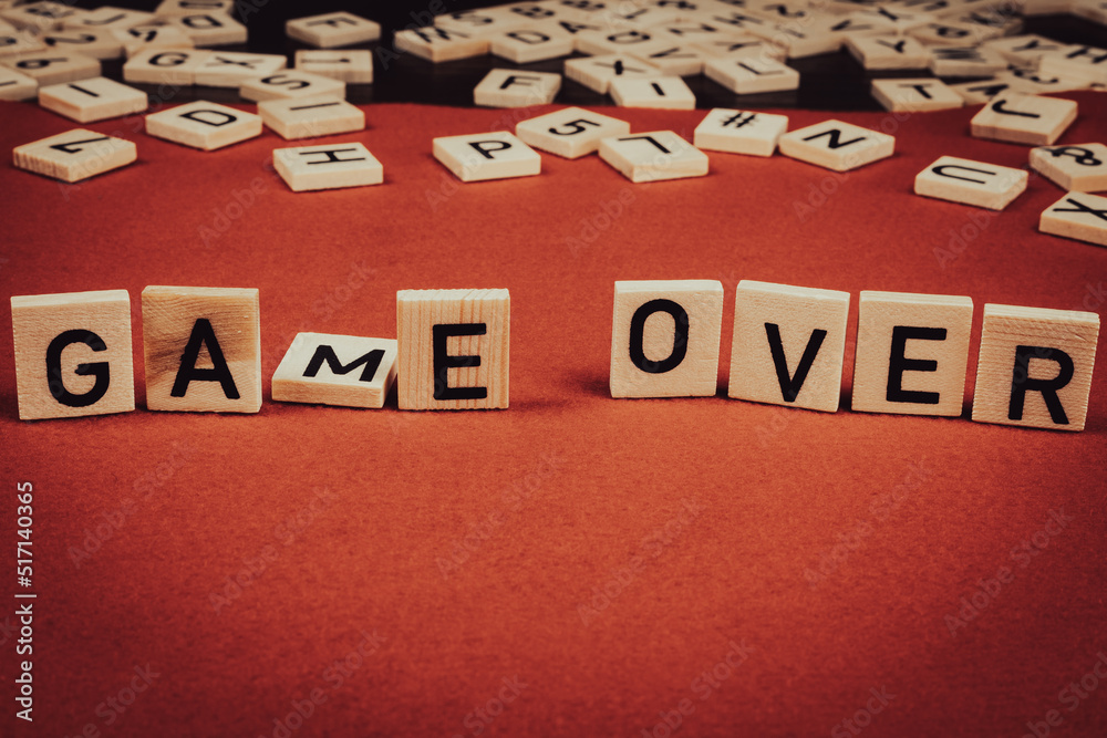 "Game over" phrase composed of wooden tiles with letters on a red felt ...