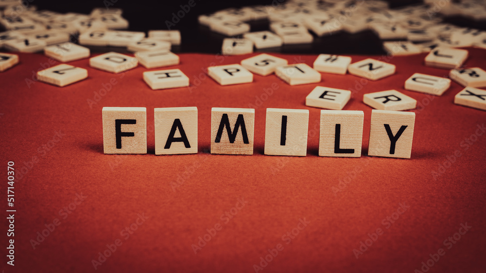 Word "Family" composed of wooden tiles with letters on a red felt ...