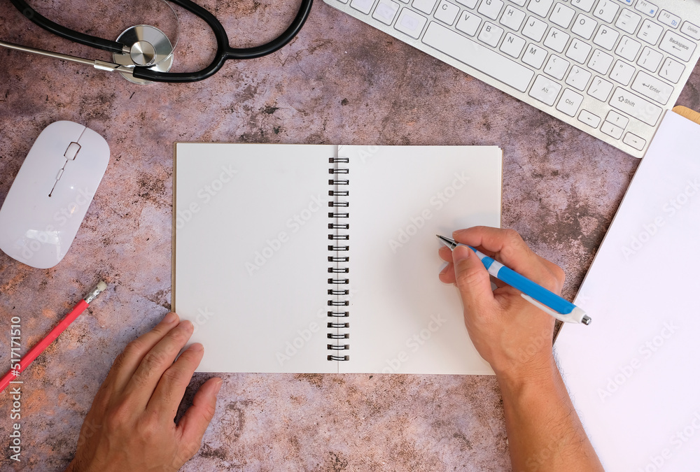 Man writing on a blank page of a notebook at a white, minimalist office ...