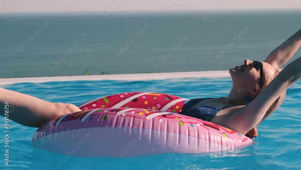 Beautiful girl in a blue swimsuit and sunglasses enjoys relaxing in the ...