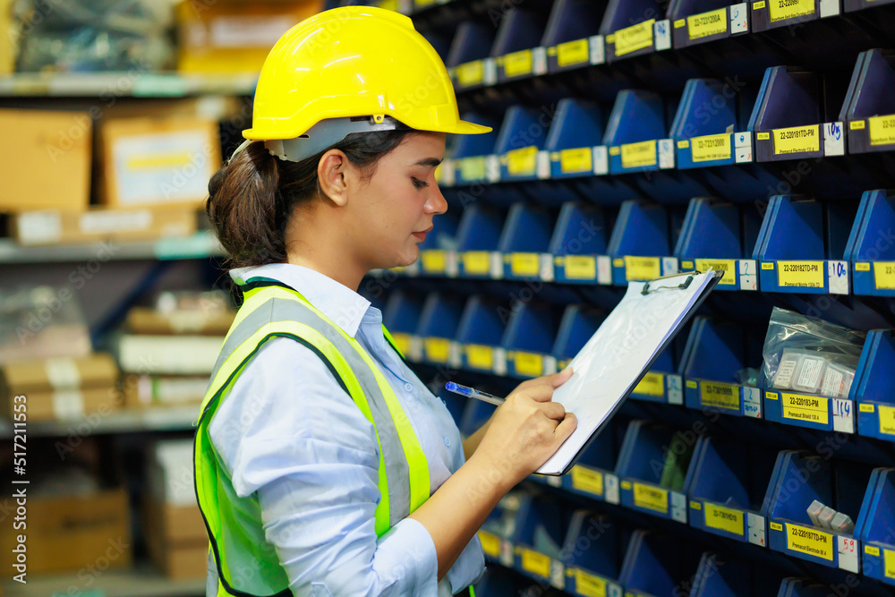 Happy female factory manager checking order on cardboard in industrial ...