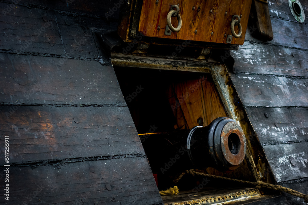 Antique cannon pointing out of the hatch from the outside of a historic ...