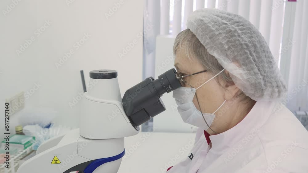 Doctor looking into the microscope instrument examining the blood ...