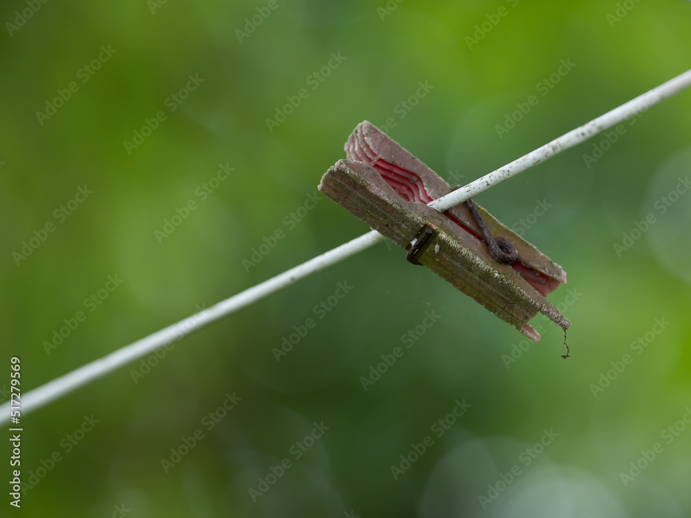 Clothespin hanging on an empty laundry line outside in a garden. A ...