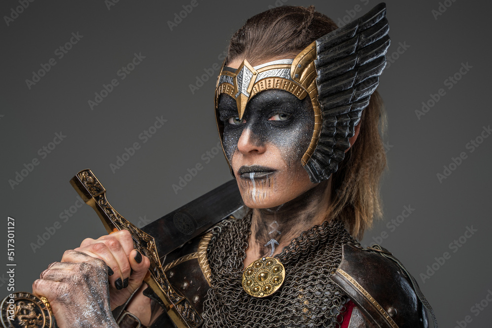 Shot of valkyrie dressed in ancient dark armor holding sword on her ...