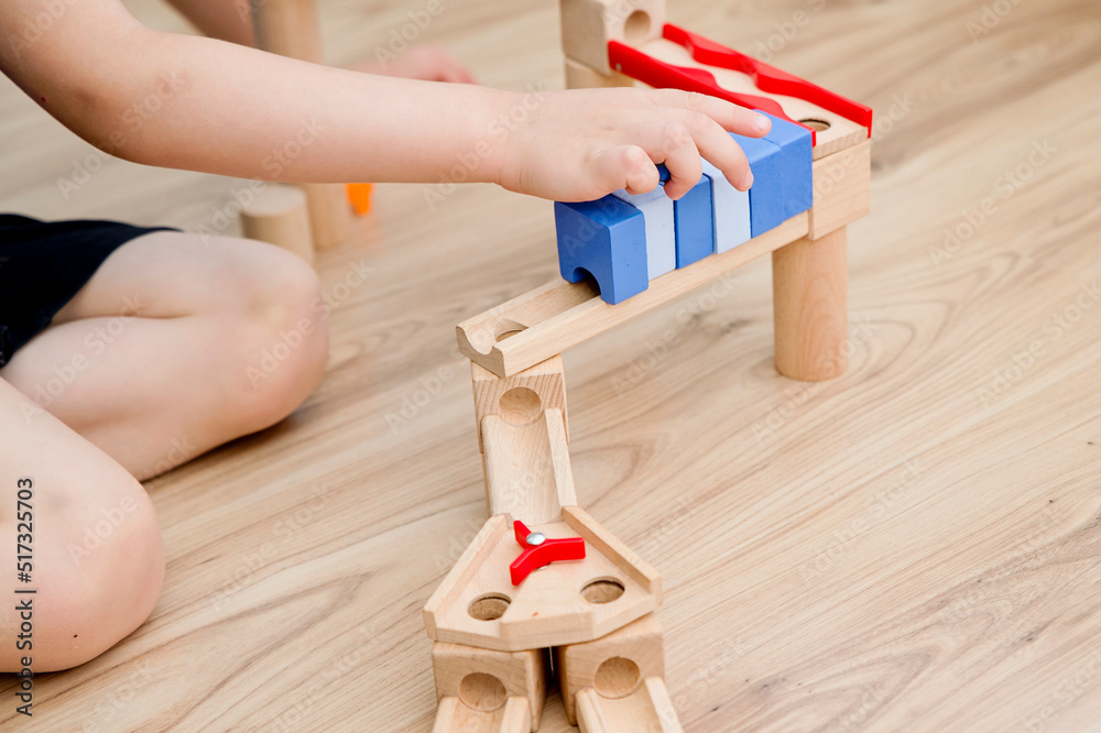 Cascading marble run. Children play with wooden track and balls. A fun ...