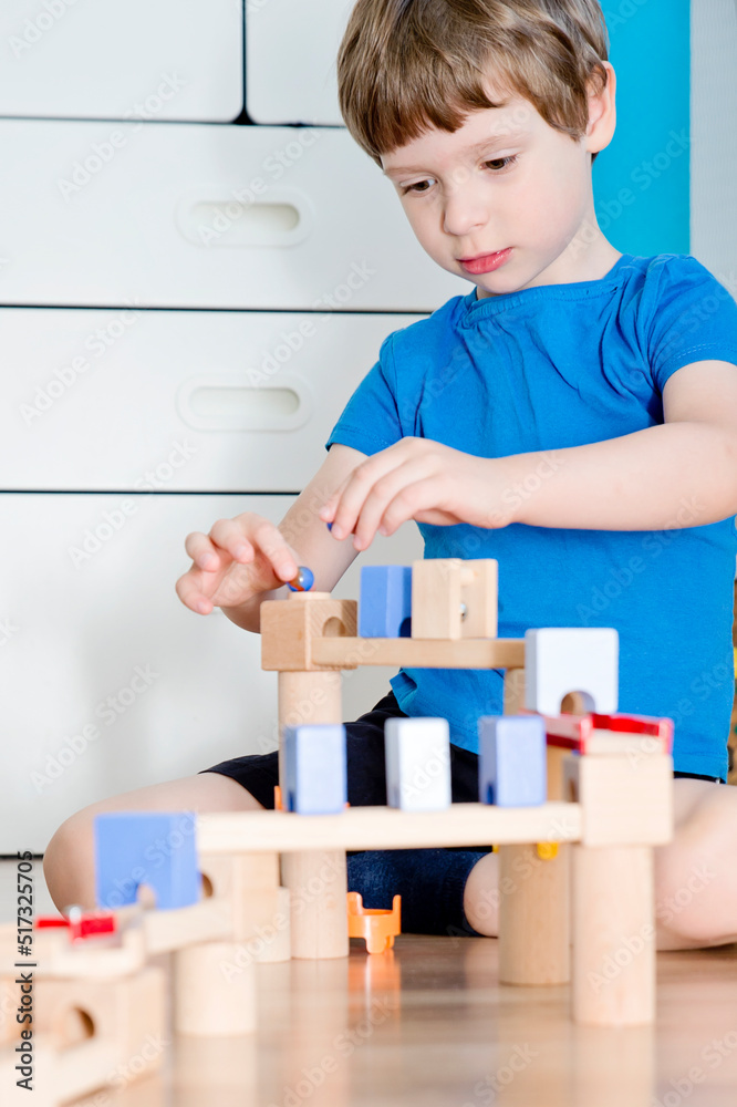 Cascading marble run. Children play with wooden track and balls. A fun ...