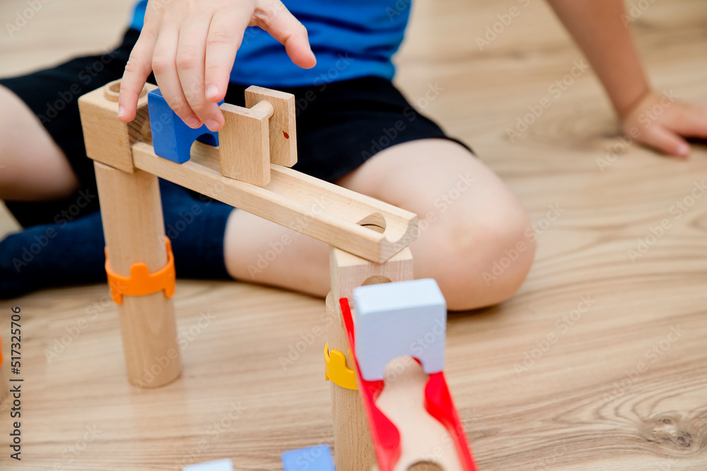 Cascading marble run. Children play with wooden track and balls. A fun ...