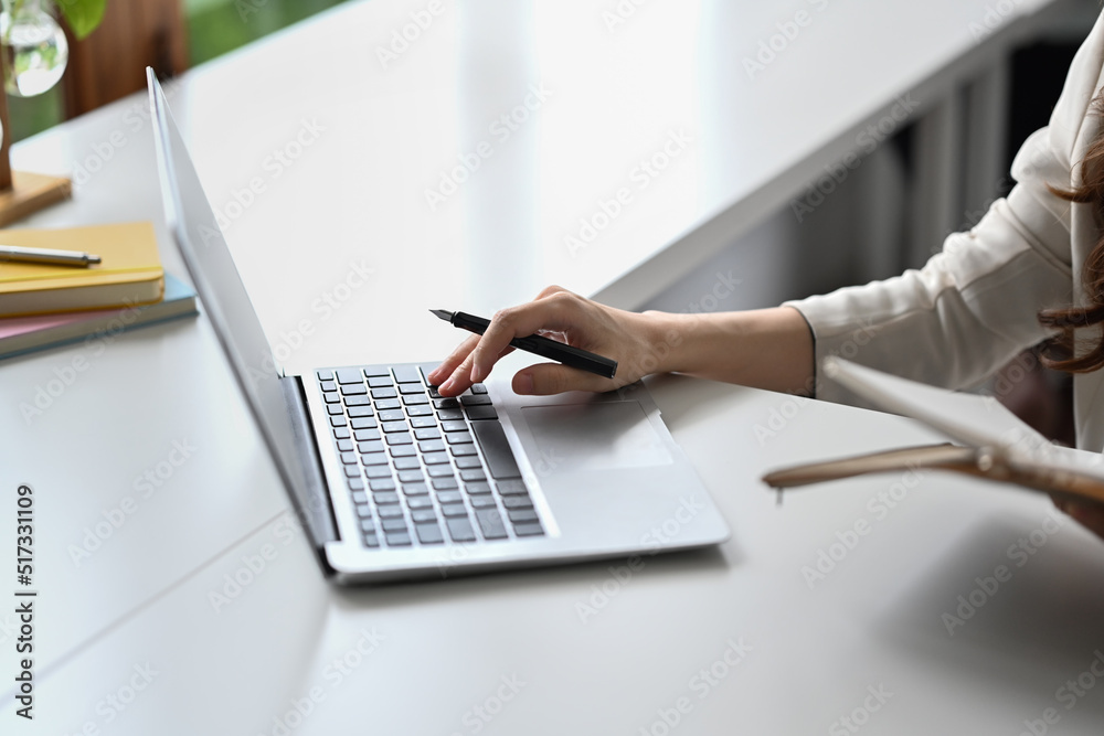 Female office worker holding notebook and working with laptop computer ...