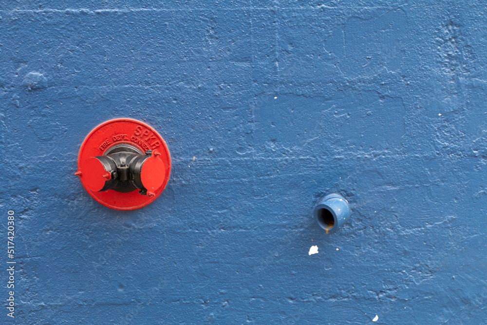 A red round sprinkler fire department access point is in a blue wall. A ...