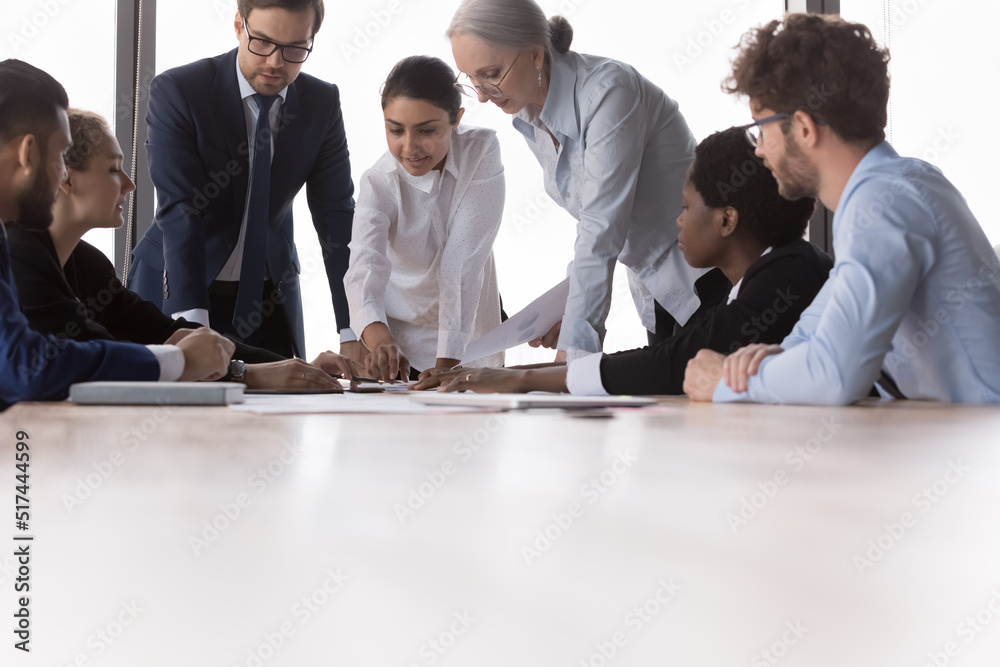 Multiethnic different aged marketing group discussing paper reports ...