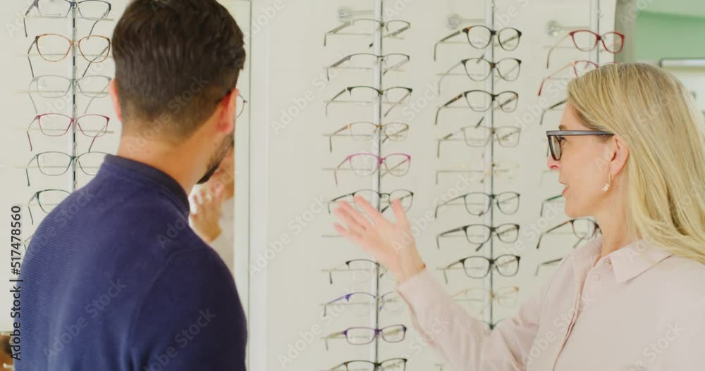 Optician helping a client choose glasses at an optometry appointment ...