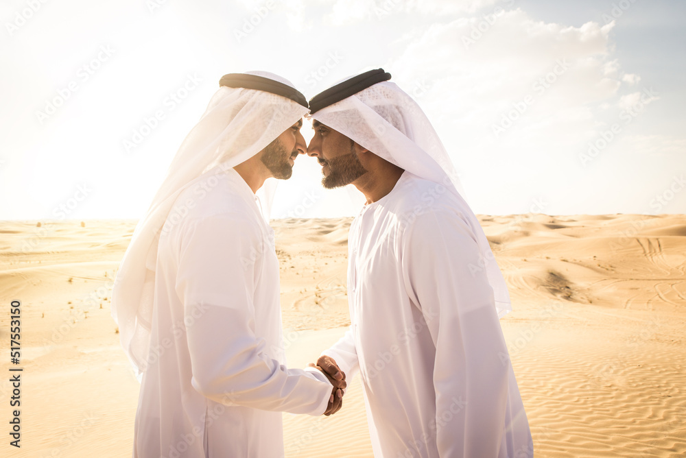 Arabic men in the desert of Dubai wearing traditional emirates clothing ...