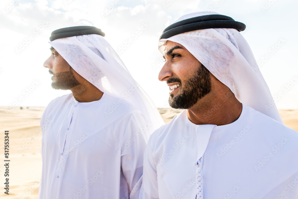 Arabic men in the desert of Dubai wearing traditional emirates clothing ...