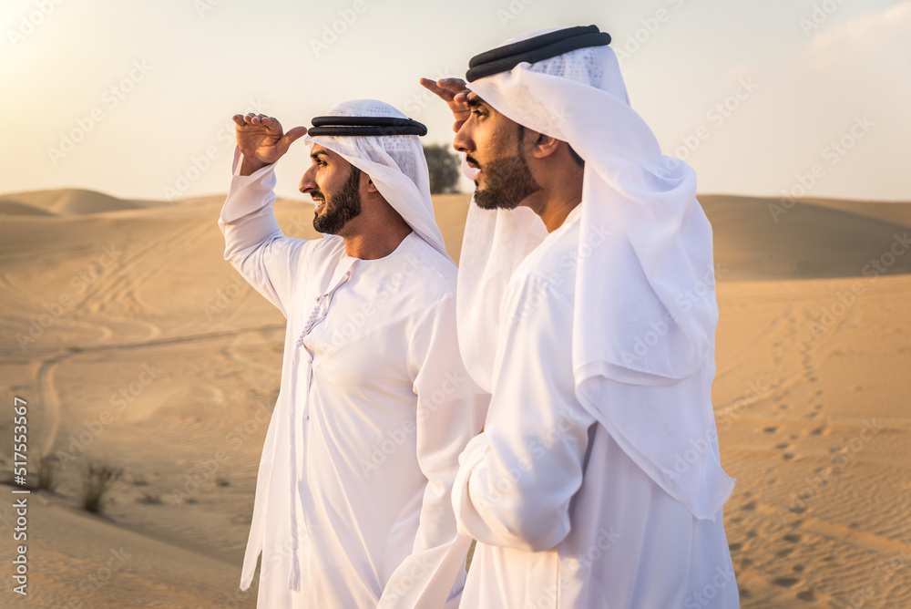 Arabic men in the desert of Dubai wearing traditional emirates clothing ...