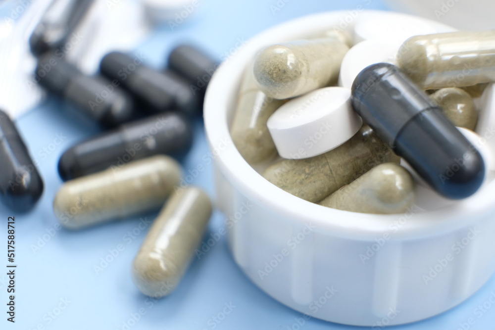 Variety of Tablets, pills, and capsules are scattered across a blue ...