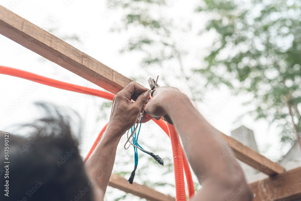 A man cutting excess wiring with a pair of combination pliers. Wires ...