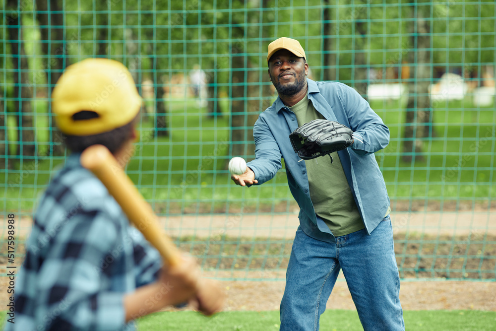 African man catching ball with glove throwing by his son during ...