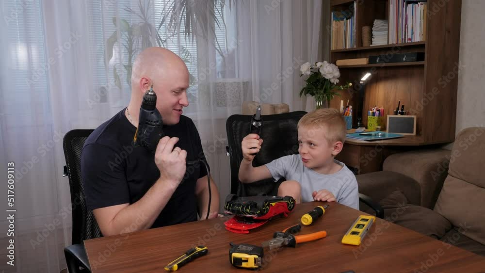 Cheerful father and son are repairing a toy car together, they have a ...