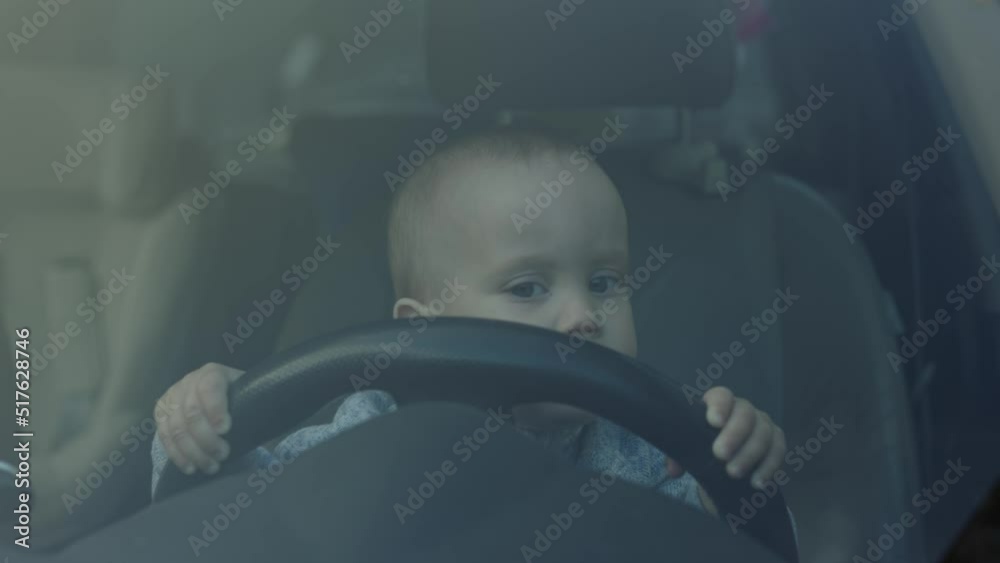 baby drives car, holding steering wheel, playing in vehicle alone, left ...