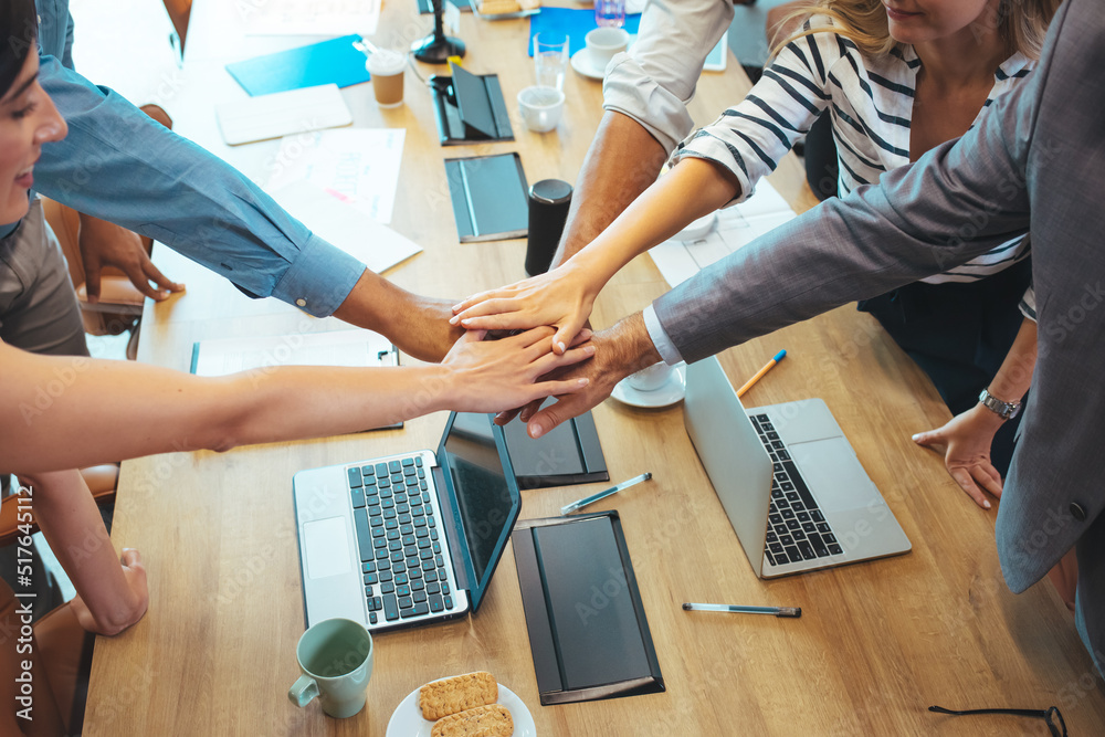 Shot of a group of businesspeople high fiving while sitting in a ...
