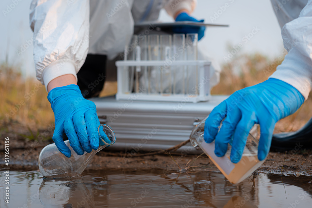 Ecologist taking samples of water with test tube from city river to ...