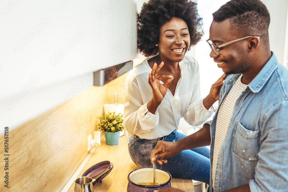 Happy black couple cooking and tasting healthy food in kitchen ...