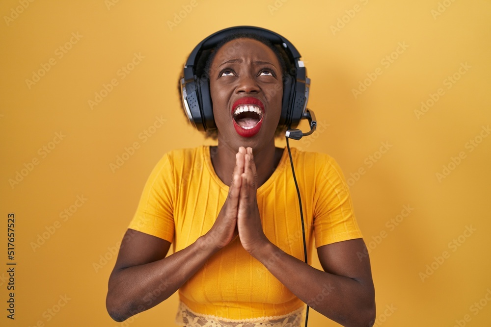African woman with curly hair standing over yellow background wearing ...